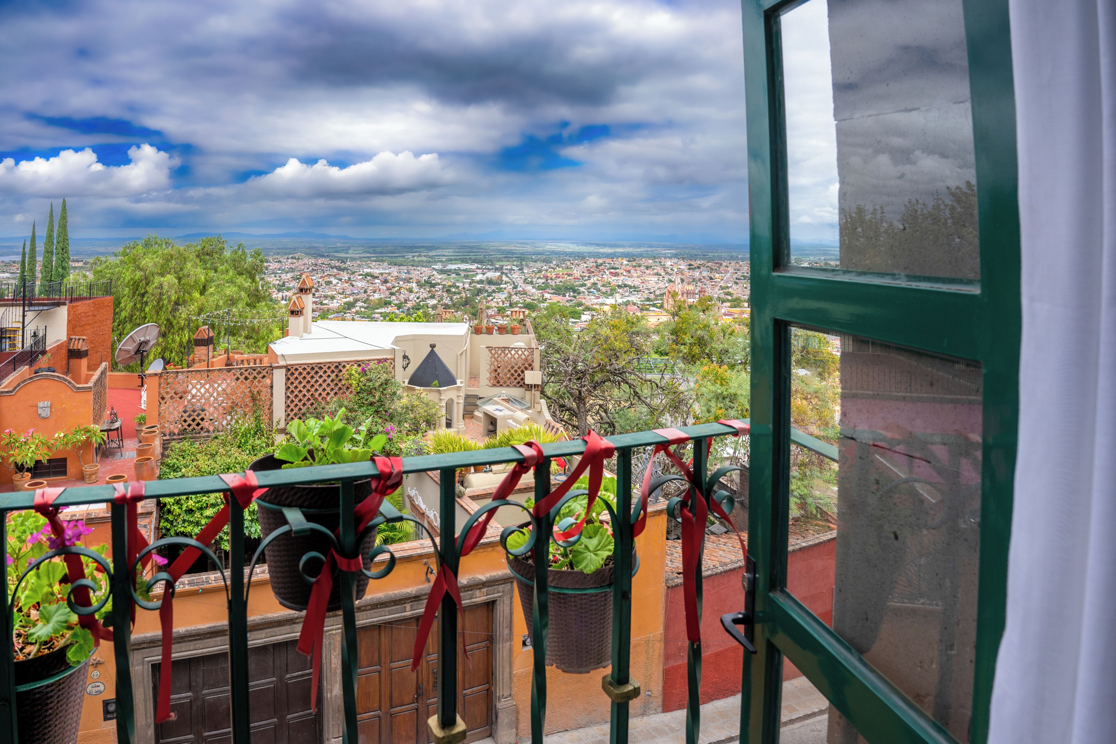 Uma varanda com vista para um horizonte urbano, incluindo uma igreja e edifícios residenciais.