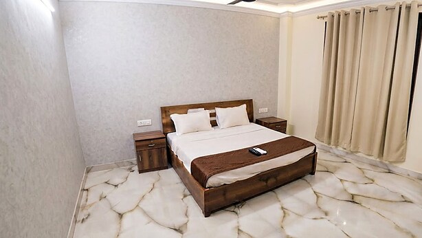 Quarto com cama de madeira, mesas de cabeceira, controle remoto e piso de mármore.
