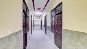 Um corredor com portas em ambos os lados, chão em mosaico e teto com iluminação embutida.