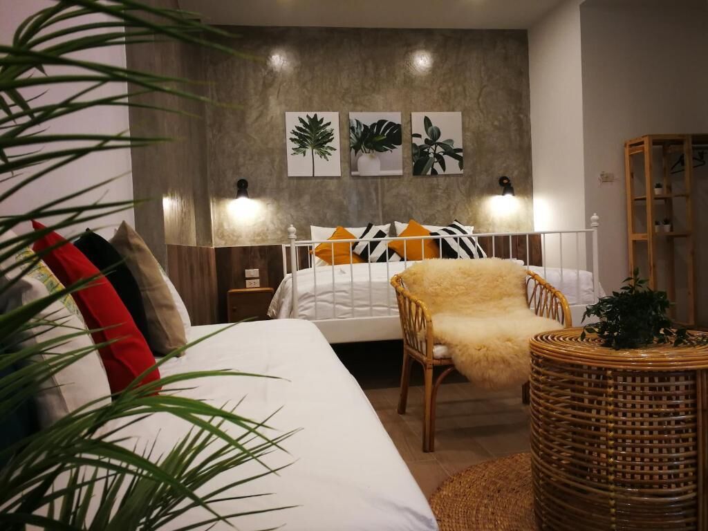Um quarto com cama, uma cadeira, mesa de cabeceira e luminárias fixadas na parede.