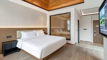 Quarto de hotel moderno com uma cama grande, teto de madeira, televisão e porta deslizante.