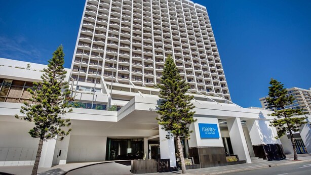 Um hotel moderno com fachada imponente, vários andares e céu aberto.