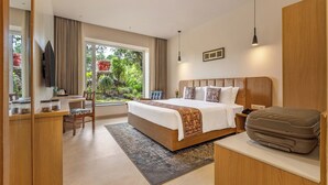 Quarto de hotel moderno com uma cama grande, uma escrivaninha, uma cadeira, uma televisão e uma mala.