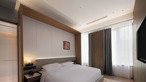 Quarto de hotel com uma cama grande, mesas de cabeceira, televisão de tela plana e janela com cortinas.
