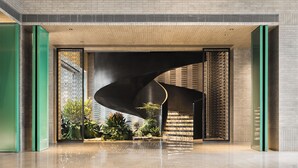 Um hall espaçoso com um mural tradicional, uma escultura moderna e vista para um edifício.