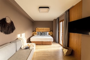 Quarto com uma cama grande, um sofá, uma televisão e uma cabeceira de madeira.