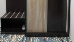Um quarto com um guarda-roupa escuro, um painel de madeira e uma estante.