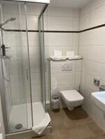 Um banheiro moderno com chuveiro de vidro, vaso sanitário e pia.