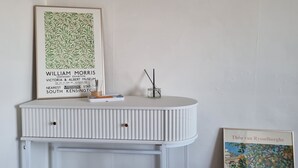 Um armário branco com textura em relevo, com uma obra de arte emoldurada acima e outra, menor, à direita.