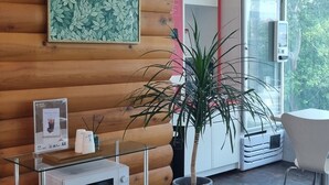 Um interior moderno com parede de madeira, uma planta em vaso, micro-ondas e máquina de vendas.