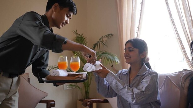 Alguém servindo suco de laranja para outra pessoa sentada em um sofá.