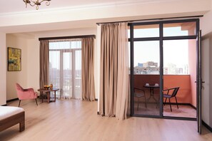 Uma sala de estar moderna com uma cama, uma mesa de jantar com cadeiras e uma varanda com vista para a cidade.