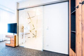 Quarto com porta de correr, televisão de tela plana e armário de madeira.