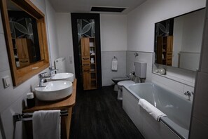 Uma casa de banho moderna com banheira, duas pias e sanita.