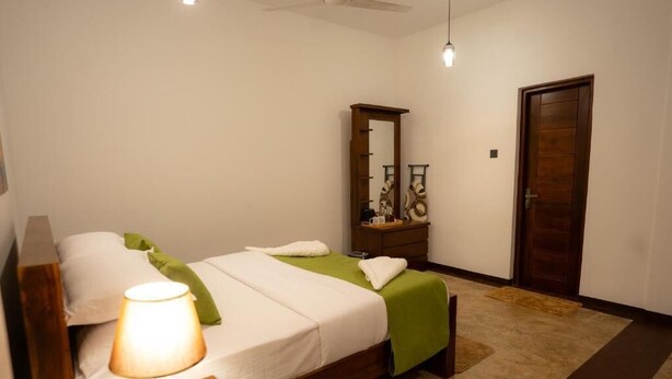 Quarto com cama, mesa de cabeceira, abajur e espelho.