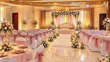 Espaço para casamentos com mesas, cadeiras e palco decorado com flores.