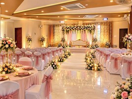 Espaço para casamentos com mesas, cadeiras e palco decorado com flores.