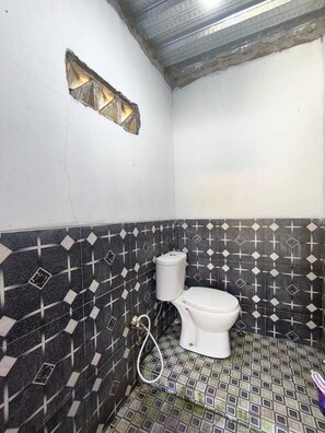 Uma casa de banho pequena com sanita, lavatório e paredes em azulejo.