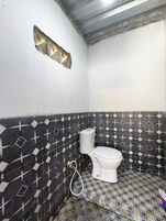 Uma casa de banho pequena com sanita, lavatório e paredes em azulejo.