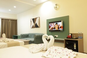 Quarto de hotel com duas camas, um sofá, uma televisão e um minibar.