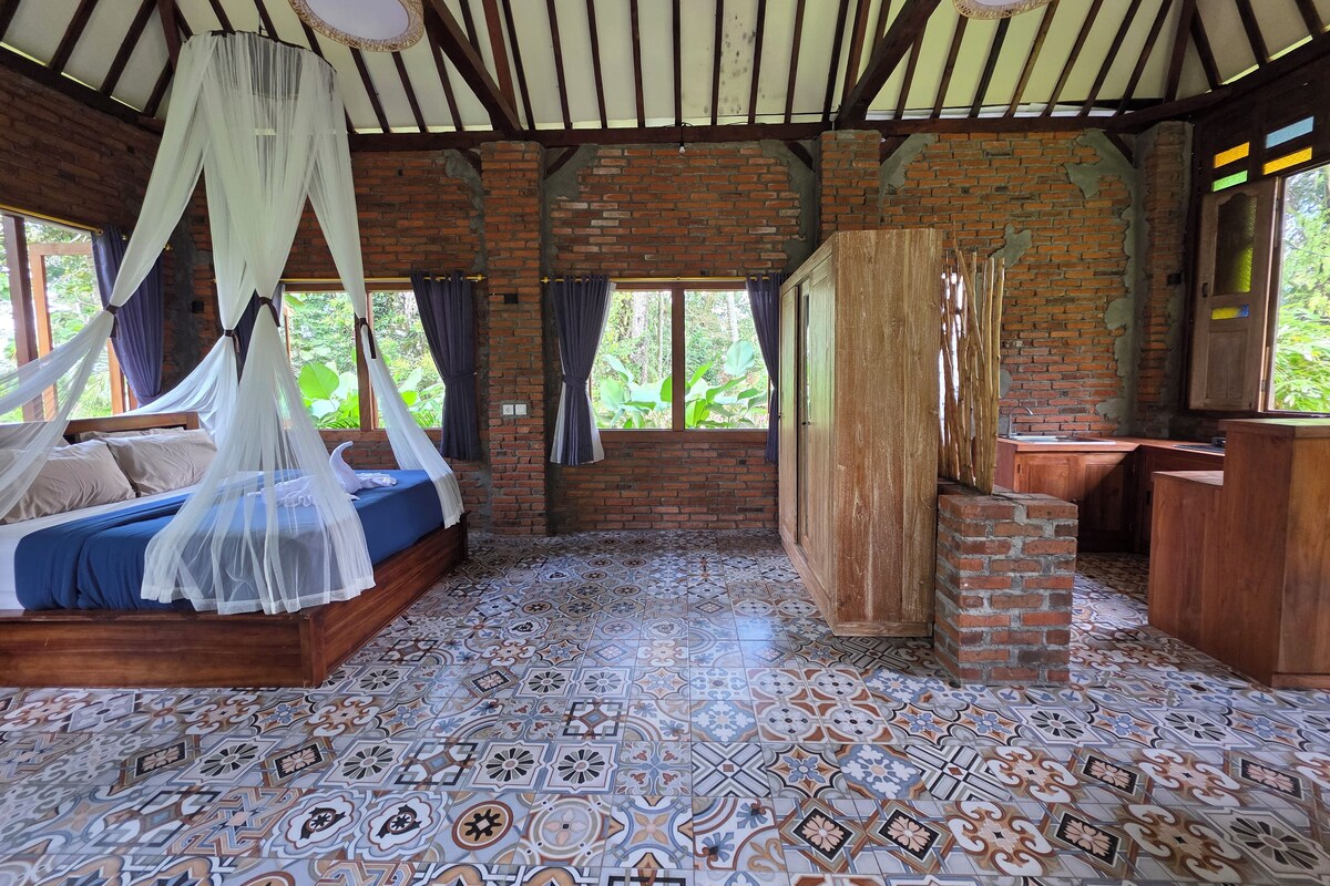 Quarto com cama, pia e vista para o verde.