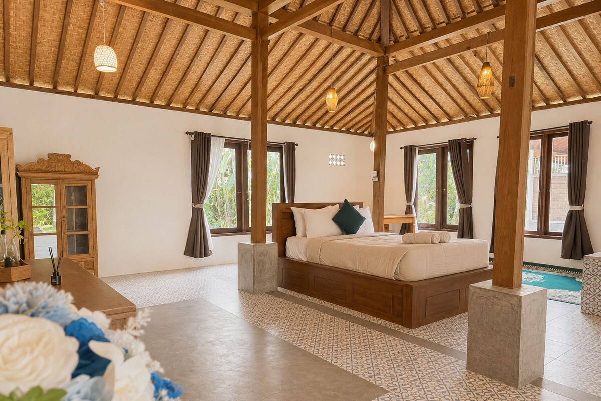 Um quarto espaçoso com uma cama grande, vigas de madeira e vista para o verde.