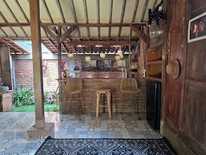 Um espaço de bar rústico com paredes de tijolo, vigas de madeira e ladrilhos estampados.