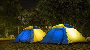 Duas tendas montadas em um ambiente natural, com árvores ao fundo.