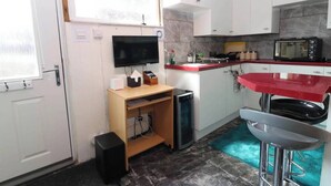 Uma cozinha compacta com televisão integrada, micro-ondas e frigorífico pequeno.