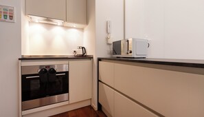 Uma cozinha moderna com forno embutido, micro-ondas e chaleira sobre a bancada.