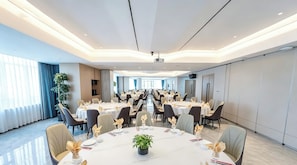 Uma sala de conferências moderna com mesas redondas, cadeiras e um projetor no teto.