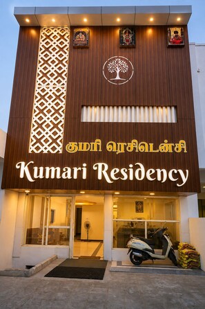 Um edifício com uma placa que indica 'Kumari Residency' e um logotipo de árvore acima da entrada.