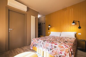 Quarto com cama, luminária de cabeceira, radiador e armário.