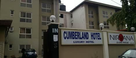 Placa do Hotel Cumberland, um hotel de luxo, com uma área de estacionamento e uma pessoa próxima.