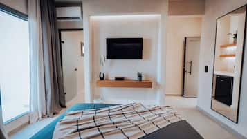 Um quarto moderno com cama, televisão na parede, prateleira embutida e porta para um banheiro.