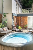 Uma piscina ao ar livre com deck de madeira, espreguiçadeiras e uma pequena área ajardinada.