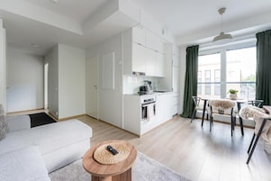 Um apartamento moderno com sala de estar, cozinha, área de refeições e uma grande janela com cortinas.