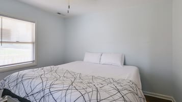 Quarto com uma cama, ventilador de teto e janela com persianas.