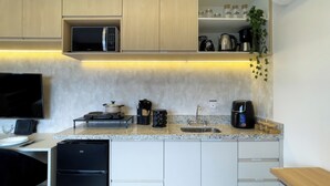 Uma cozinha moderna com micro-ondas embutido, fogão, pia e máquina de café.