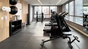 Uma academia moderna com equipamentos de ginástica, um dispensador de toalhas e vista da cidade através de grandes janelas.