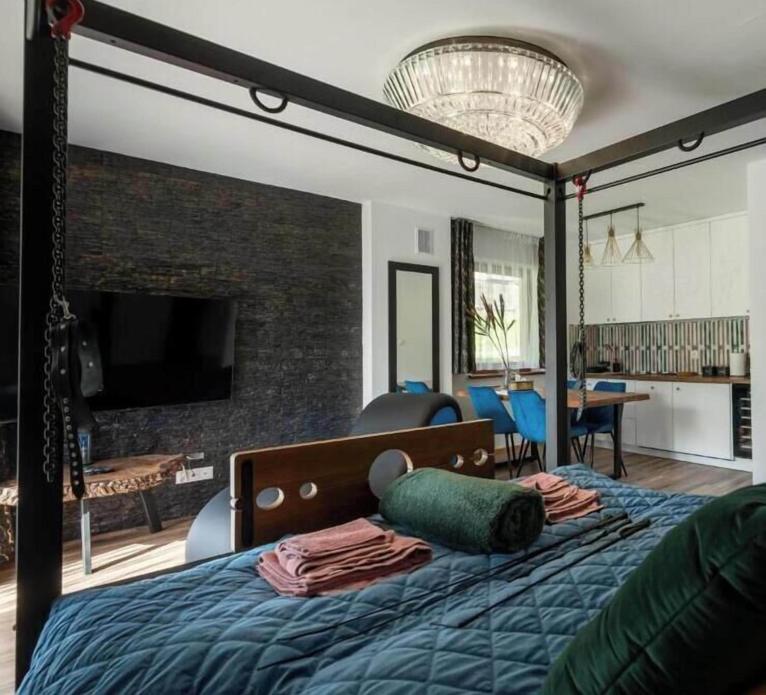 Um quarto moderno com cama, televisão na parede e um espaço de refeições com cadeiras e mesa.