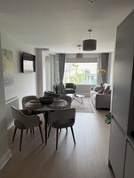 Um espaço de estar moderno com área de jantar, sofá e vista para o exterior.