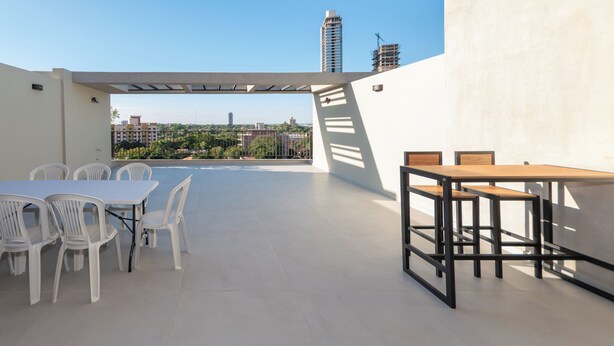 Terraço no terraço com uma mesa de jantar e cadeiras, uma pequena mesa de madeira e vista para a cidade.