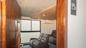 Quarto com ventoinha no teto, janela com persianas e dois poltronas de couro reclináveis.
