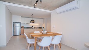 Uma cozinha moderna com área de jantar, cadeiras brancas e mesa de madeira.