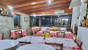 Um restaurante com tetos de madeira, paredes de pedra e mesas com toalhas xadrez vermelhas e brancas.