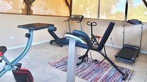 A gym with exercise equipment including a treadmill, elliptical, and stationary bike.