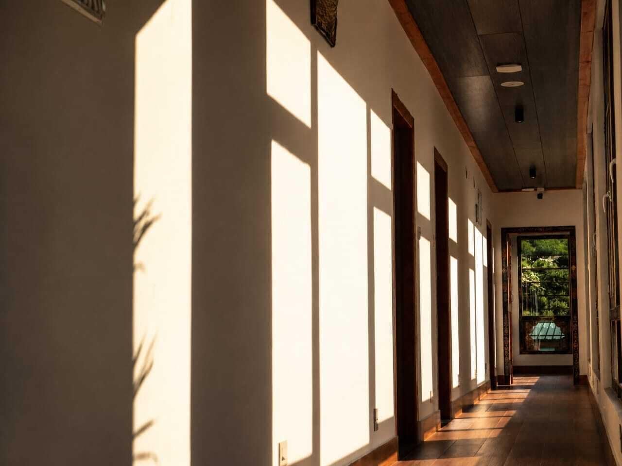 Um corredor com várias portas e janelas que permitem a entrada de luz natural.