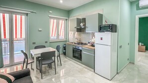 Uma cozinha moderna com fogão a gás, forno, micro-ondas e frigorífico. Há uma área de refeições com mesa e cadeiras.