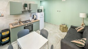 Um espaço compacto com cozinha compacta, área de refeições e sala de estar com sofá e mesa.